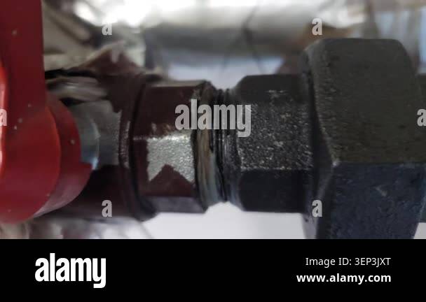 Horizontal tracking shot of a copper pipe connection with a large black ...
