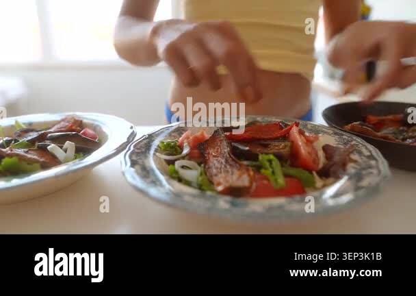 Close-up of adult hands arranging sliced red produce into a bowl during ...