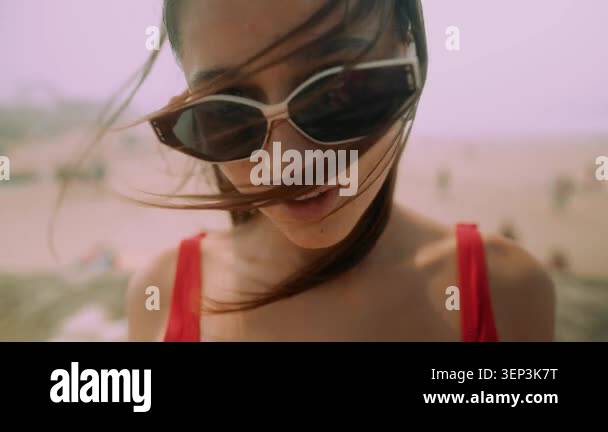 Woman red swimsuit closeup windblown, sunglasses slipping through hair ...