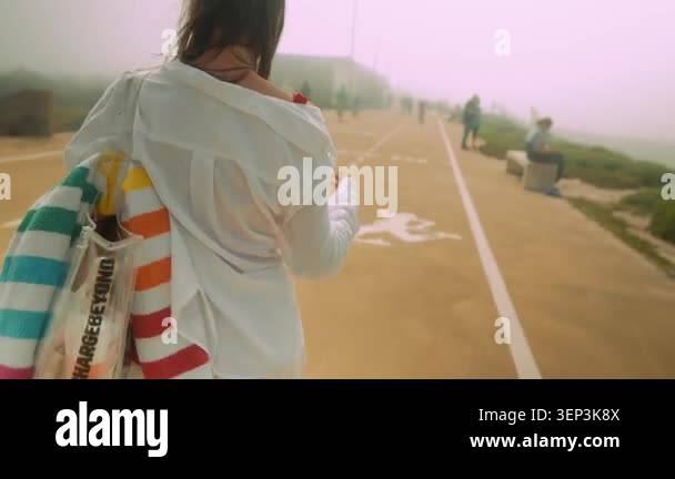 Young white woman walking beach path, red swimsuit, white coverup ...