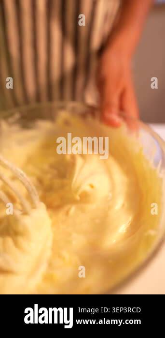 Closeup hands cracking egg into batter, careful shell handling, striped ...