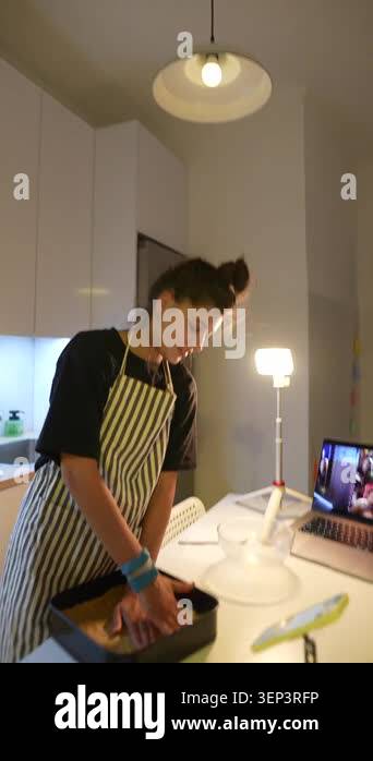 Young woman livestream cooking crust tutorial under warm lamp laptop on ...