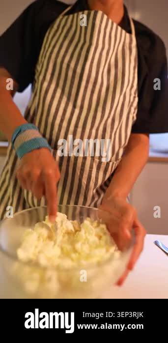 Young woman stirring creamy filling bowl striped apron blue wristbands ...