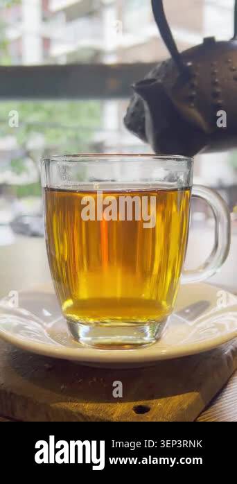 Close up of hot herbal tea being poured from a traditional cast iron ...