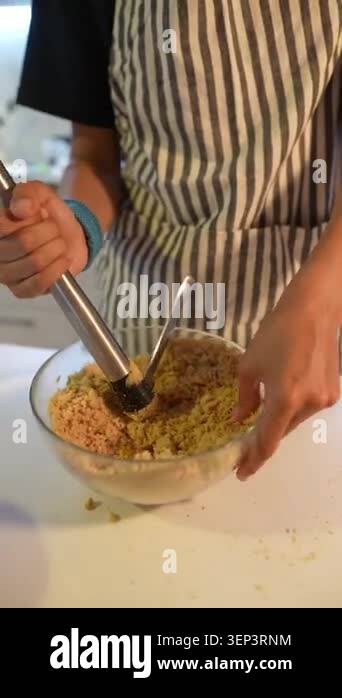 Closeup hands pounding crumb mixture in bowl, striped apron and blue ...