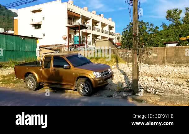 Sporty pickup truck parked in tropical Thai city surrounded by palm ...