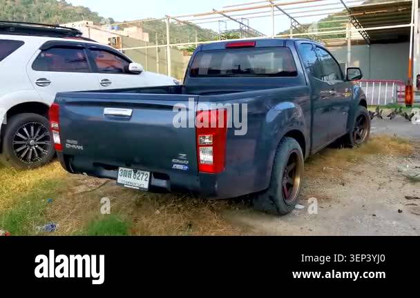 Sporty pickup truck parked in tropical Thai city surrounded by palm ...