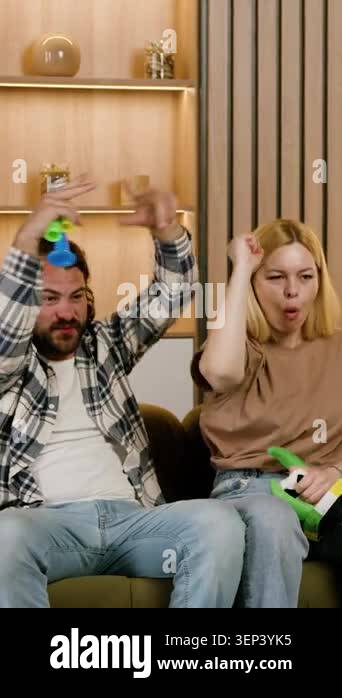 Caucasian man and woman express excitement on a couch, raising their ...