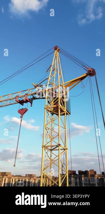 Vertical. Aerial view of a yellow industrial tower crane working on a ...