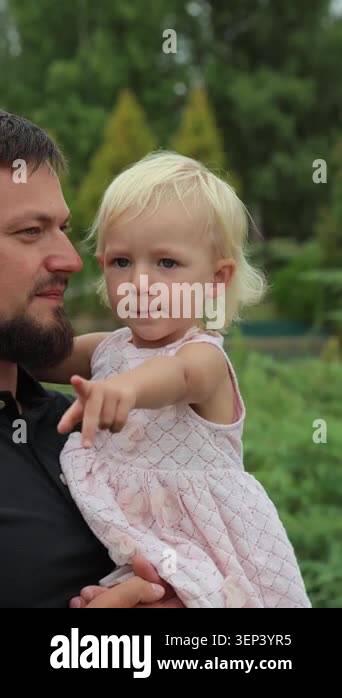 Vertical video. Happy bearded father holding his cute blonde toddler ...