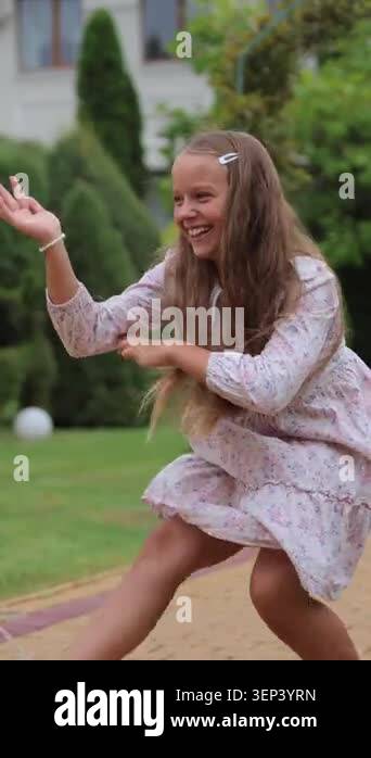 Vertical video. A cheerful young girl with long blond hair is laughing ...