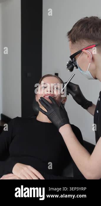 Male dentist examining the teeth of a smiling female patient sitting in ...