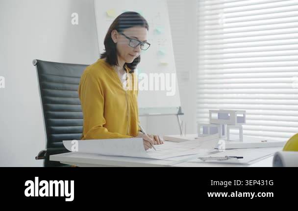 Woman architect working on building blueprints and an architectural ...