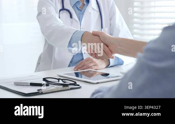 Medical professional greeting patient with warm handshake, conveying ...