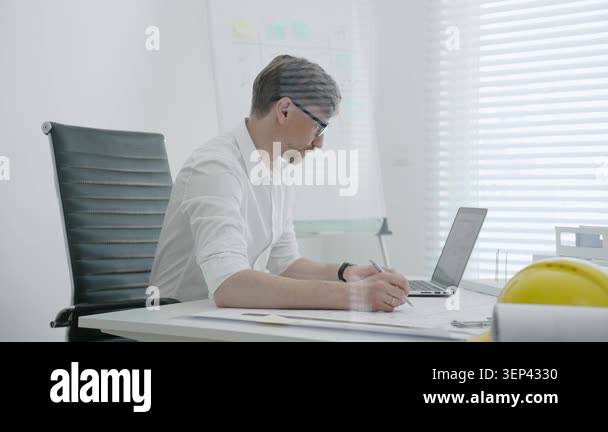 Professional male architect or engineer concentrating on blueprints and ...