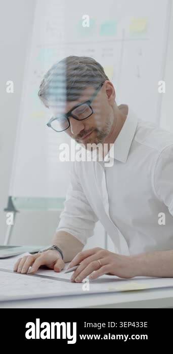 Male architect planning a new construction project, drawing on ...