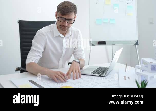 Professional male architect or engineer concentrating on blueprints and ...