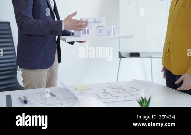 Architect presenting a contemporary building model to a collaborator ...