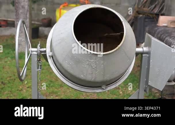 A wide shot of an empty portable cement mixer machine rotating on a ...