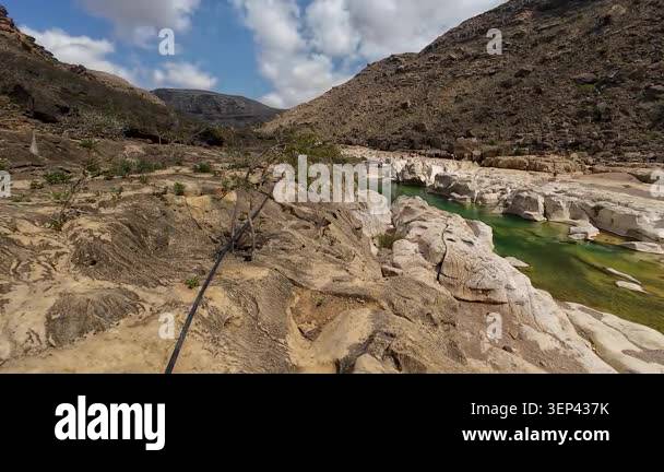 Rocky desert canyon with a clear green river, dry mountain slopes ...