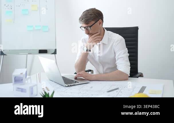 Professional male architect or engineer concentrating on blueprints and ...