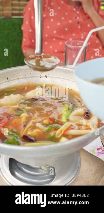 Close up of pouring authentic Thai Tom Yum Goong soup with shrimps and ...