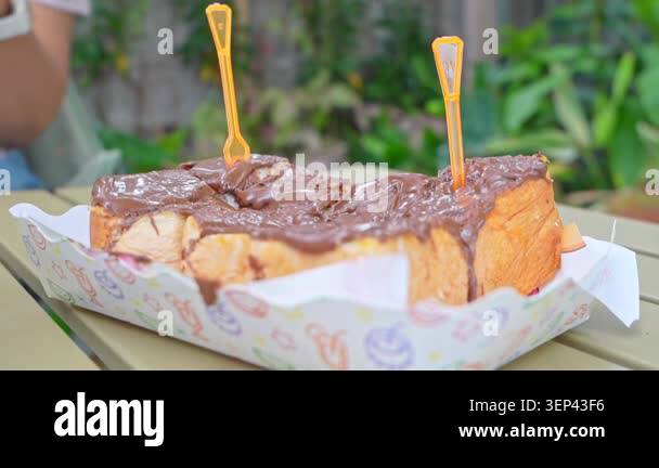 Hand pulling a piece of sweet honey toast topped with chocolate cream ...