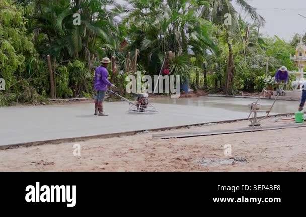 Construction workers using power trowel machine to smooth and finish ...