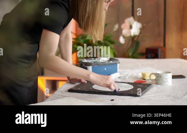 Woman uses palette knife to spread white plaster paste in a circle on ...