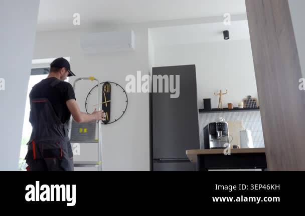 Technician checking a wall air conditioner in a bright room, climbing ...