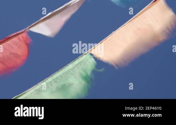 Colorful fabric flags blow in wind against blue sky with blurred ...