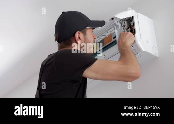 Man repairs a wall mounted air conditioner with a screwdriver. Concept ...