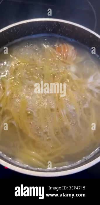 Boiling water in a saucepan cooking spaghetti and frankfurters. Close ...
