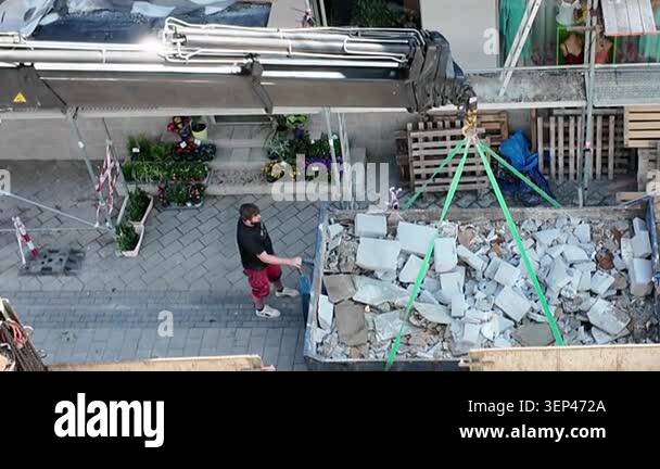 Construction worker operates crane to load debris into a dumpster for ...
