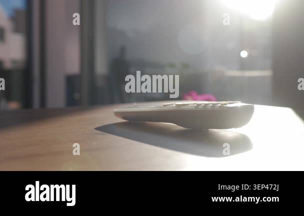 Hand taking air conditioner remote control lying on table in morning ...