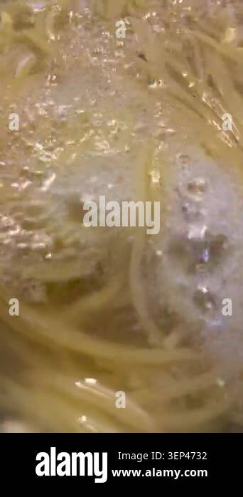 Extreme close up of yellow spaghetti pasta boiling in hot water ...