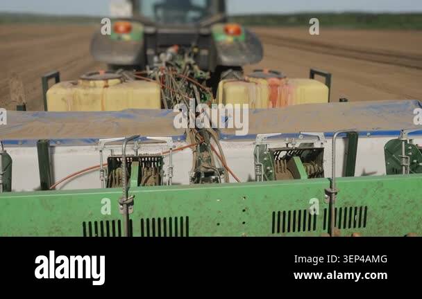 Rear view of potato planting machinery working in cultivated farmland ...