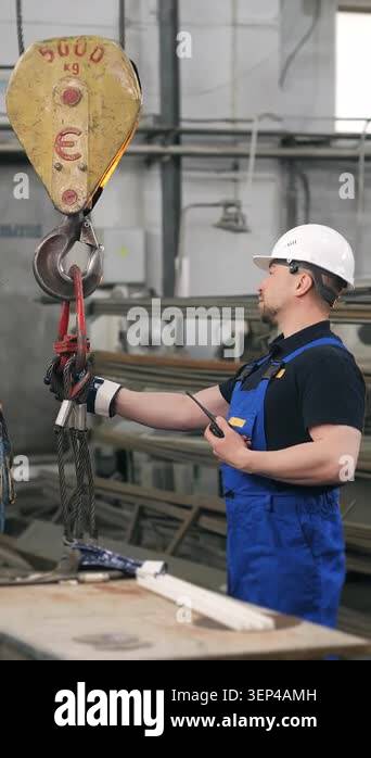 Factory worker using radio communication while operating overhead crane ...