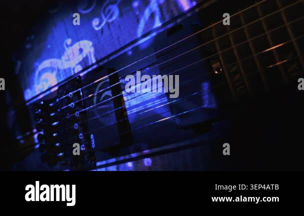 Artistic close-up of a guitar illuminated by glowing, dancing musical ...