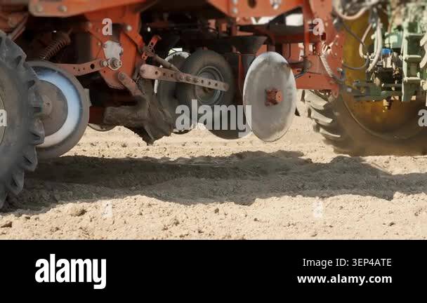 Detailed view of potato planting equipment operating on cultivated ...