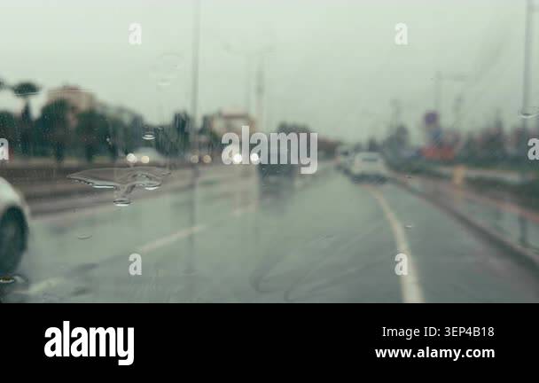 Traffic is seen through a car windshield on a rainy day, with raindrops ...
