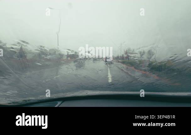 Traffic is seen through a car windshield on a rainy day, with raindrops ...
