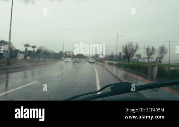Traffic is seen through a car windshield on a rainy day, with raindrops ...