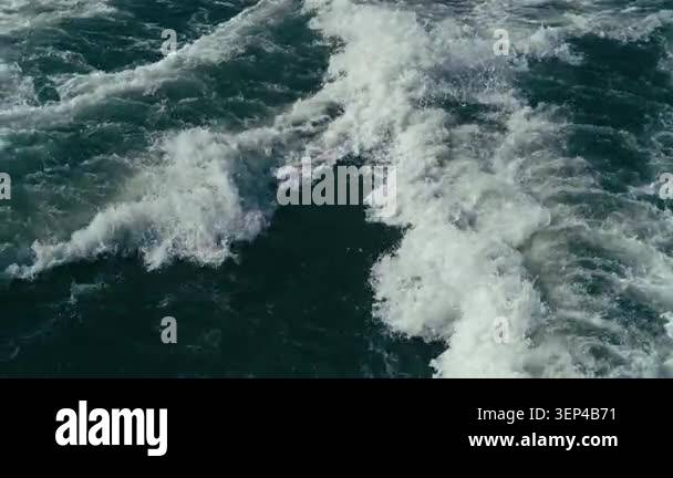 White sea foam forms dynamic wave patterns behind a moving ferry ...
