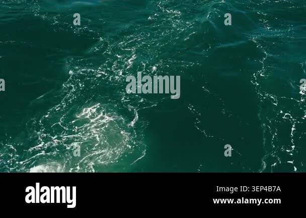 White sea foam forms dynamic wave patterns behind a moving ferry ...