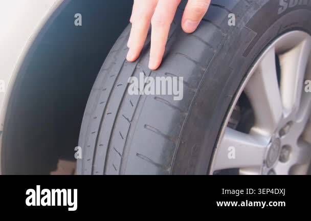 Close-up of a hand pointing at a worn and damaged car tire, checking ...