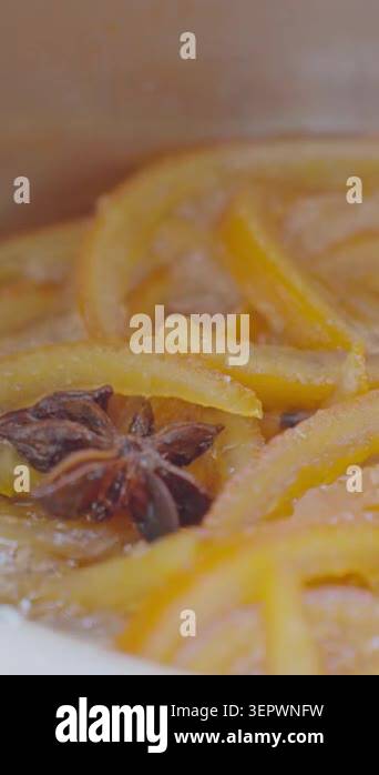 Orange peel cooks in sweet syrup with star anise in a saucepan. Concept ...
