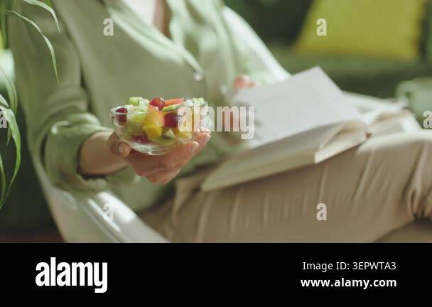 A woman relaxes in a white chair, reading a book while enjoying a ...