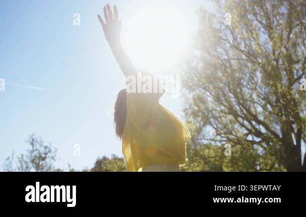 Low angle shot of a happy woman in casual clothes spinning with arms ...