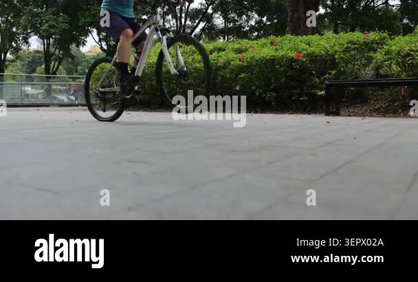 Low angle shot of a person riding a bicycle and performing a wheelie on ...